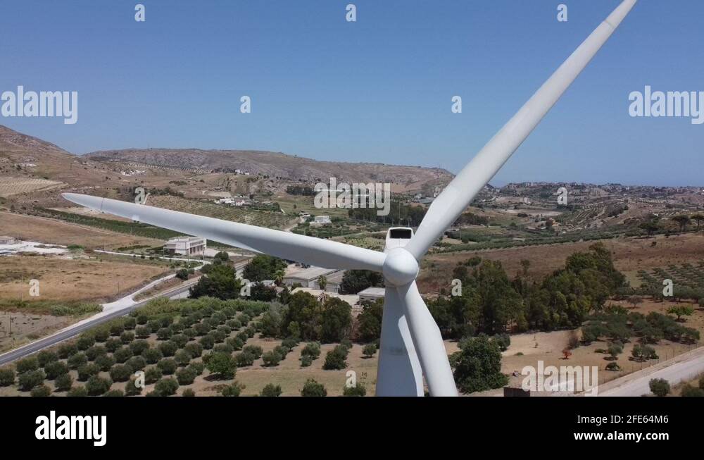 Wind turbine turning in wind on Mediterranean hilltop, aerial closeup ...