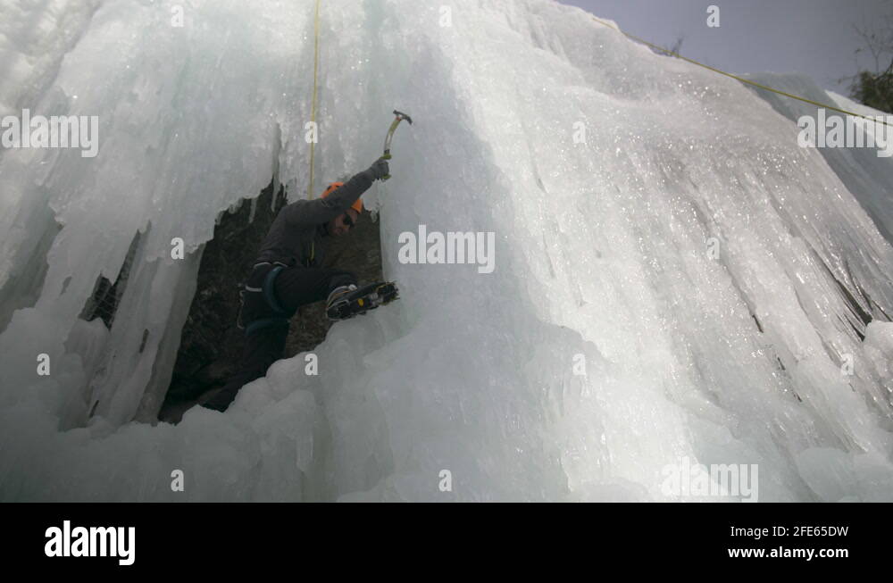An adventurous man ice climbing up a sheer frozen rock face Stock Video ...
