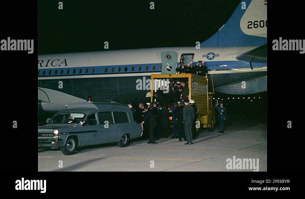 1960s: Air Force One airplane. Hearse reverses towards hydraulic lift ...