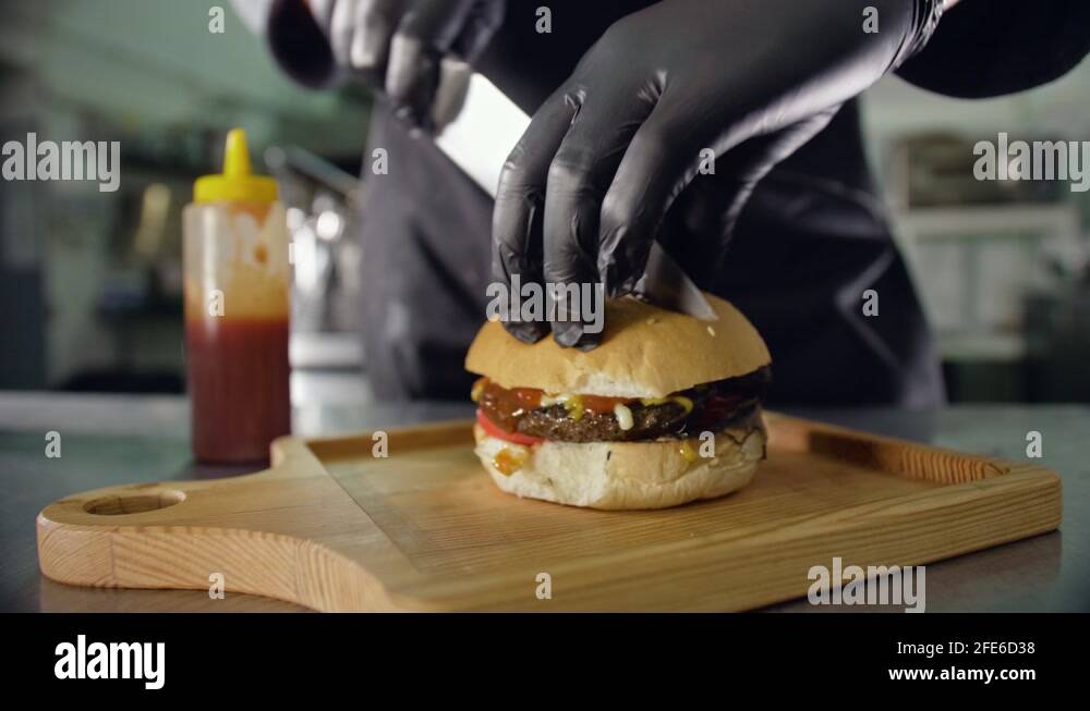 Juicy meat Burger cut in half, the chef cuts the gabmurger with a knife ...