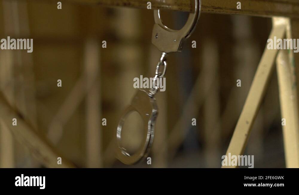 Handcuffs swinging on the handrail on a prison or arrest background ...