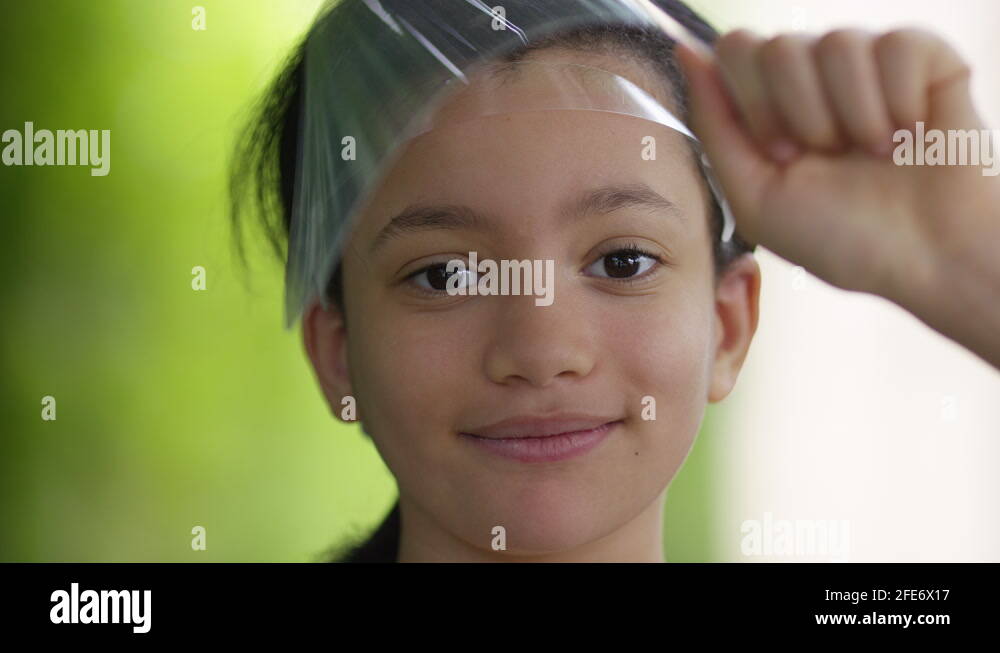 Portrait of little girl smiling as she pulls down her face shield for ...