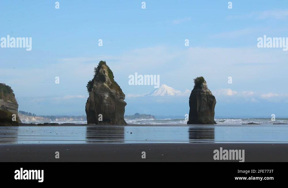 Mt Taranaki, New Zealand sits between two sea stacks over the ocean at ...
