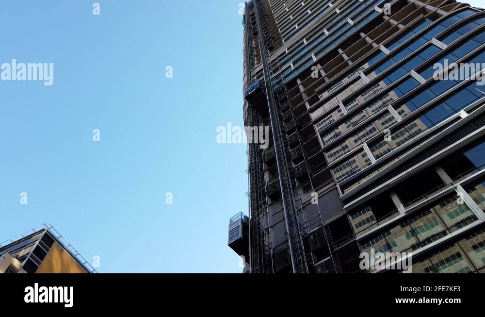 Ascending construction lift on side of building with blue sky in Sydney ...