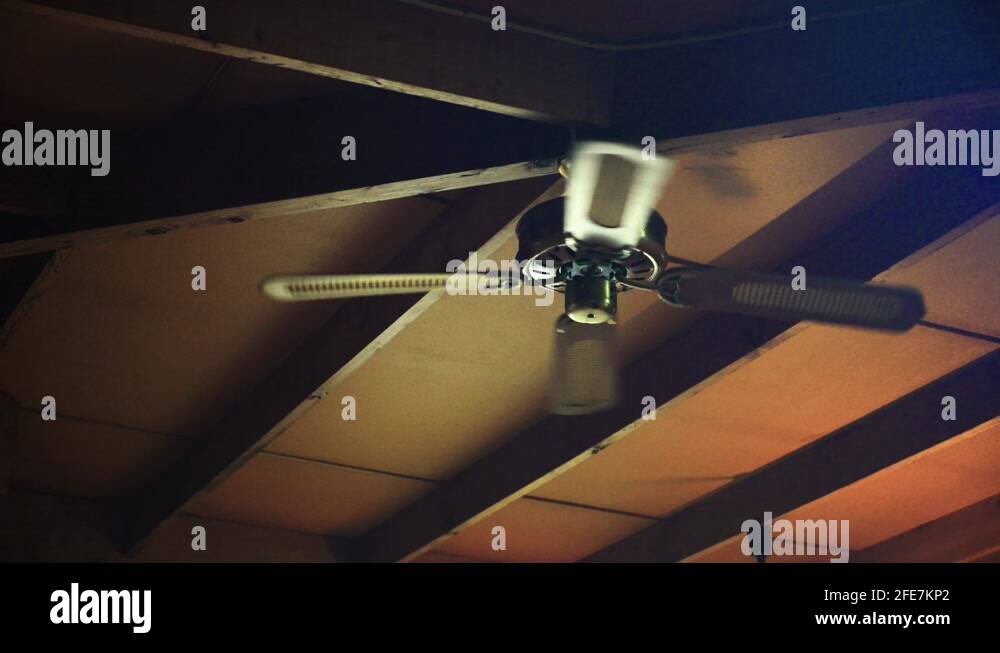 An overhead fan spinning slowly on a timber ceiling amidst wooden ...