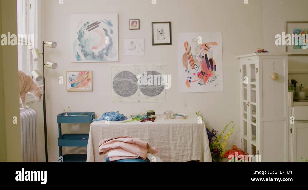 Orange Cat Jumping onto Table with art hanging into background in Stock ...