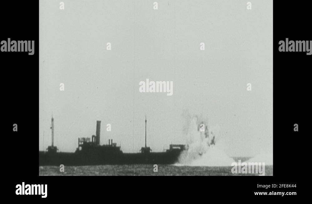 1910s: Men stand on top of submarine and fire at ship. Ship burns. Men ...