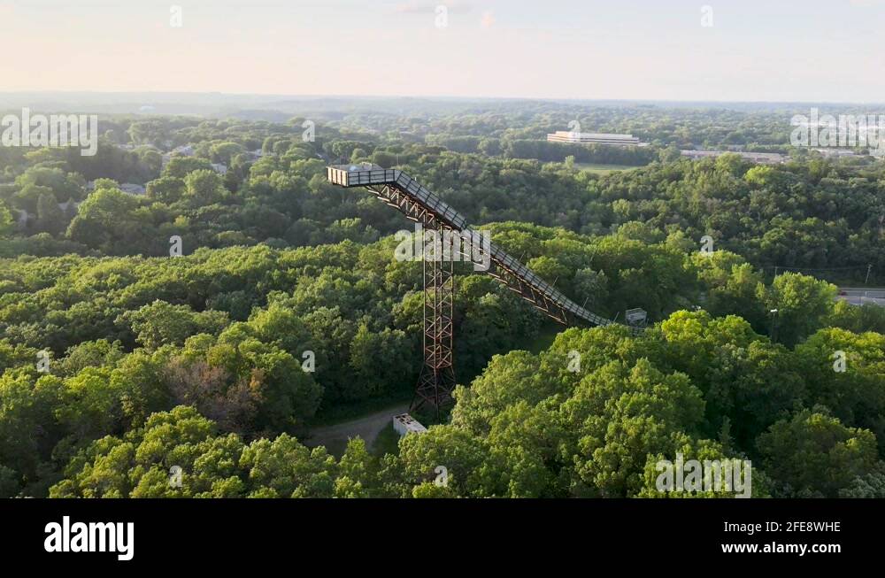 Rotating aerial view of man made ski jump track amidst dense greenery ...