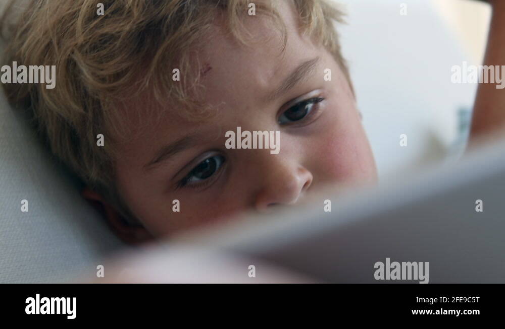 Kid face staring at screen close-up. Hypnotized child watching media ...