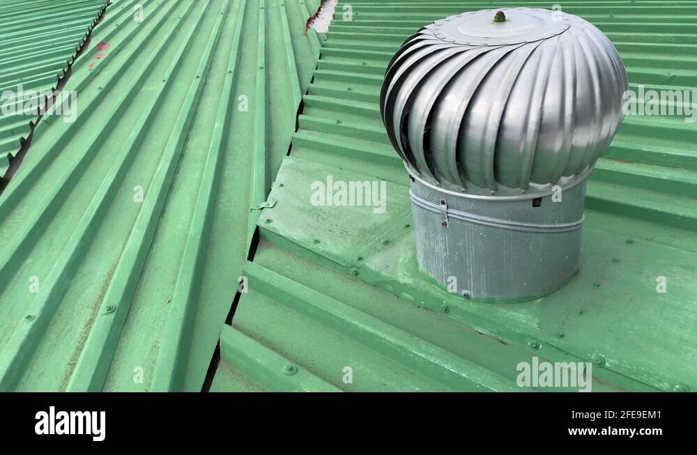 Roof wind turbine spinning on the green metal roof close to the roof ...