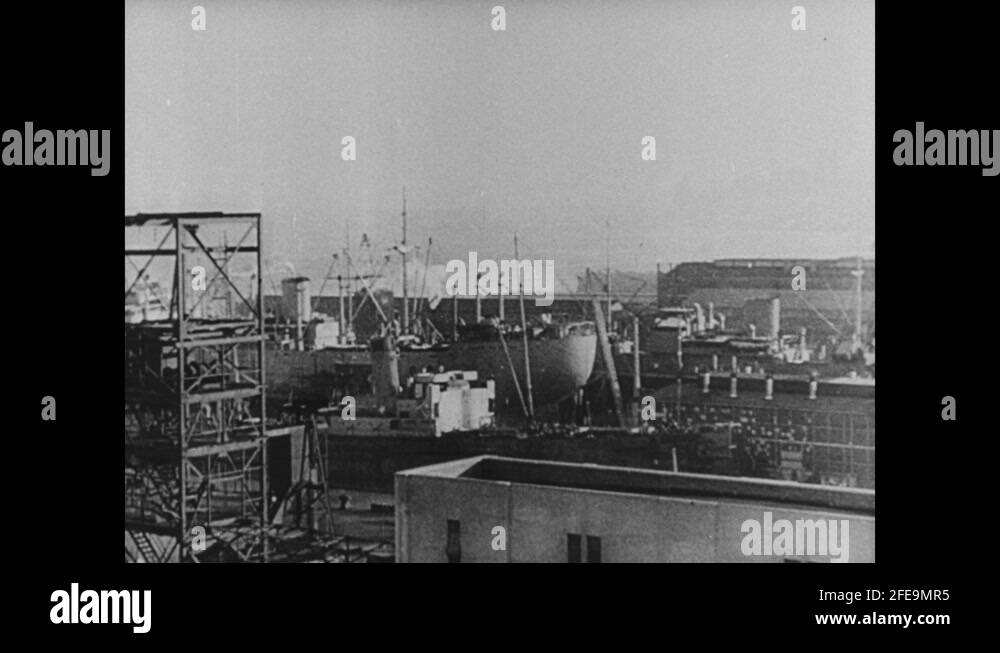 1940s: Cargo ships sit at shipyard docks. Stacks of crates and ...