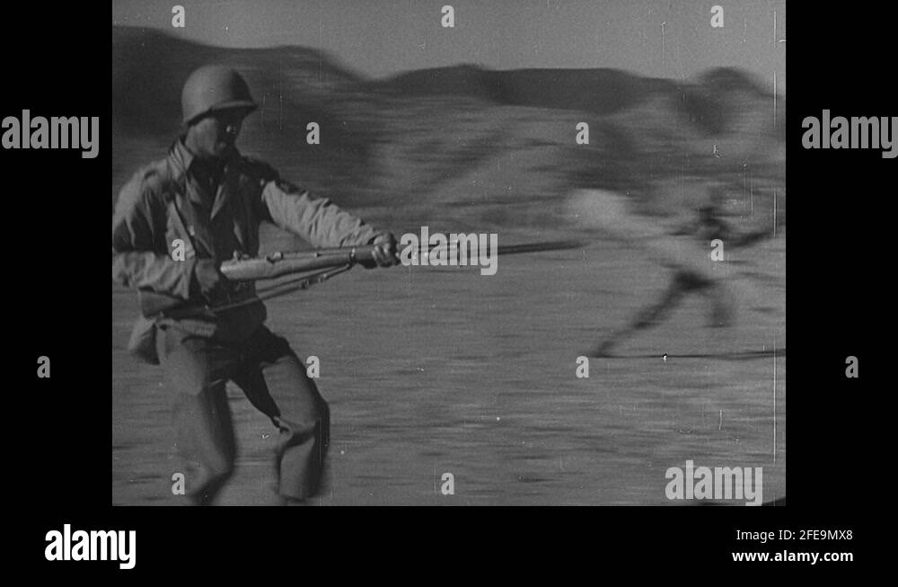 1940s: Soldiers run up to fence. Soldier run across battlefield. Flag ...