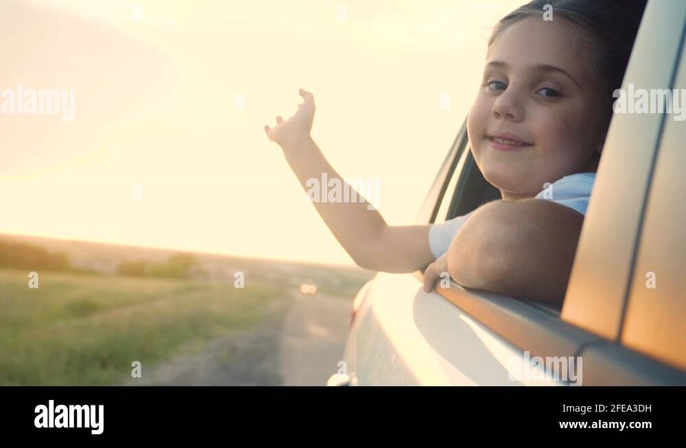 happy girl kid child smile leaned out of a car window waving hand ...