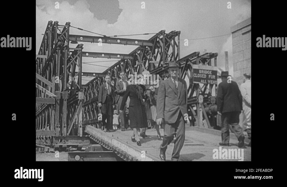 1950s Europe: Pedestrians walk across border bridge in Berlin. Workers ...