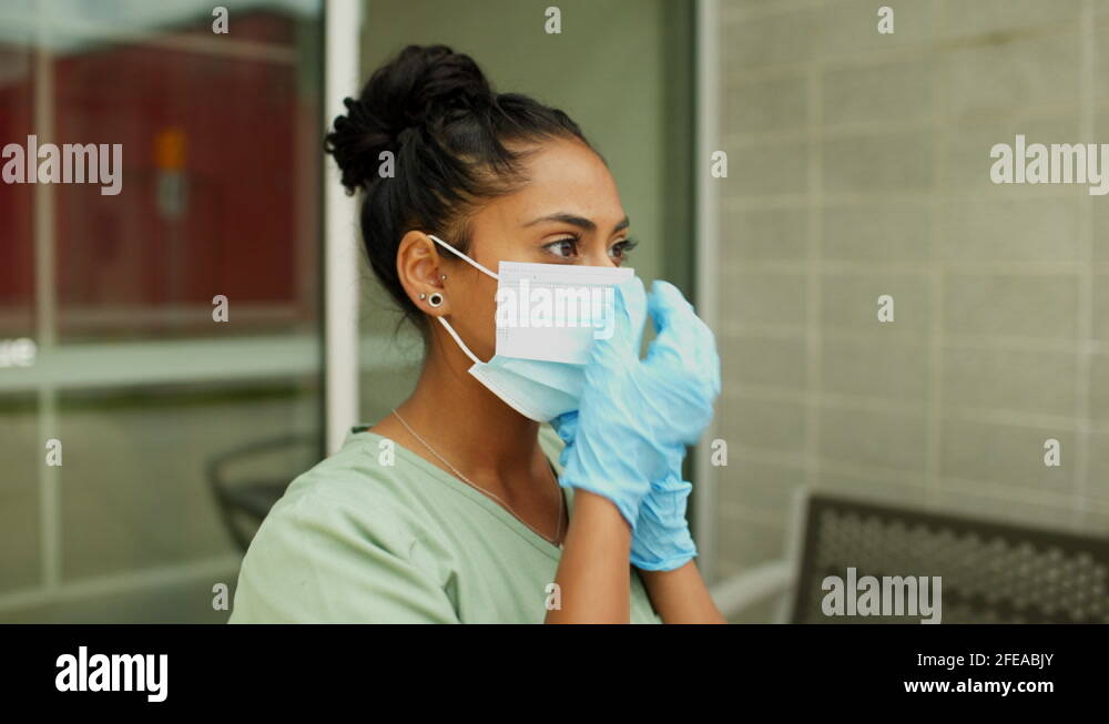 Indian, POC, nurse doctor, wearing PPE and uniform, places mask over ...