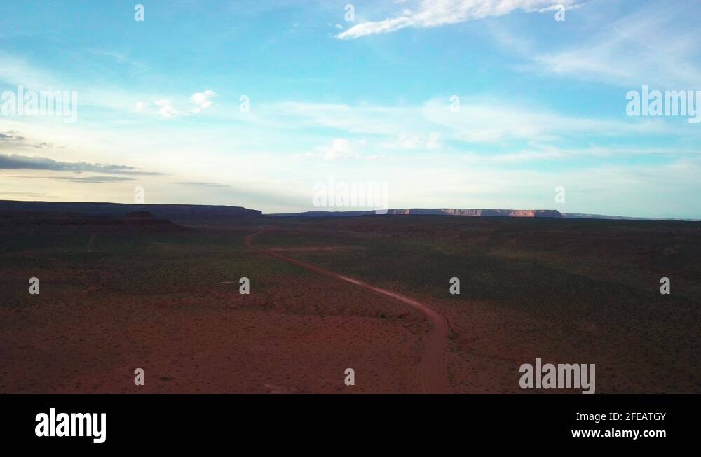 Wide shot descending over an empty desert road with a flat mesa in the ...