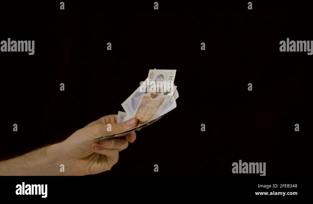 Hand waving a messy stack of cash money against a black background in ...