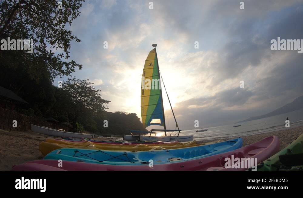 A time-lapse of a beach with a sail boat in the middle during a sunset ...
