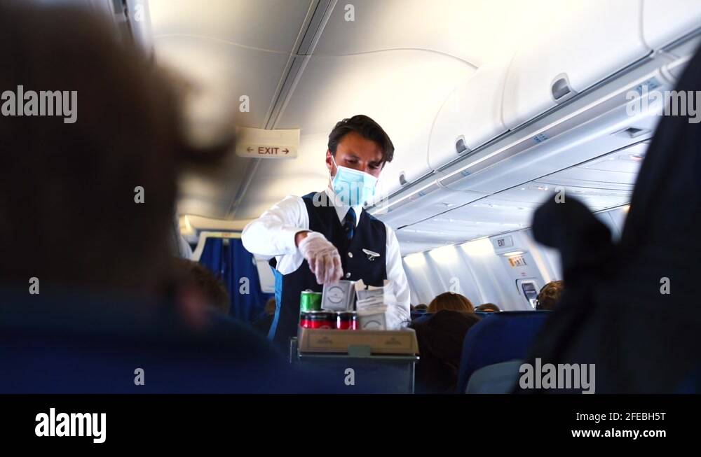 Steward with a medical face mask, gloves sorting trash aircraft board ...