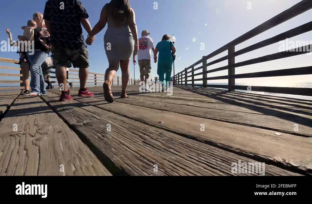 Pedestrians walking the Oceanside pier, worm's-eye view gimbal shot ...
