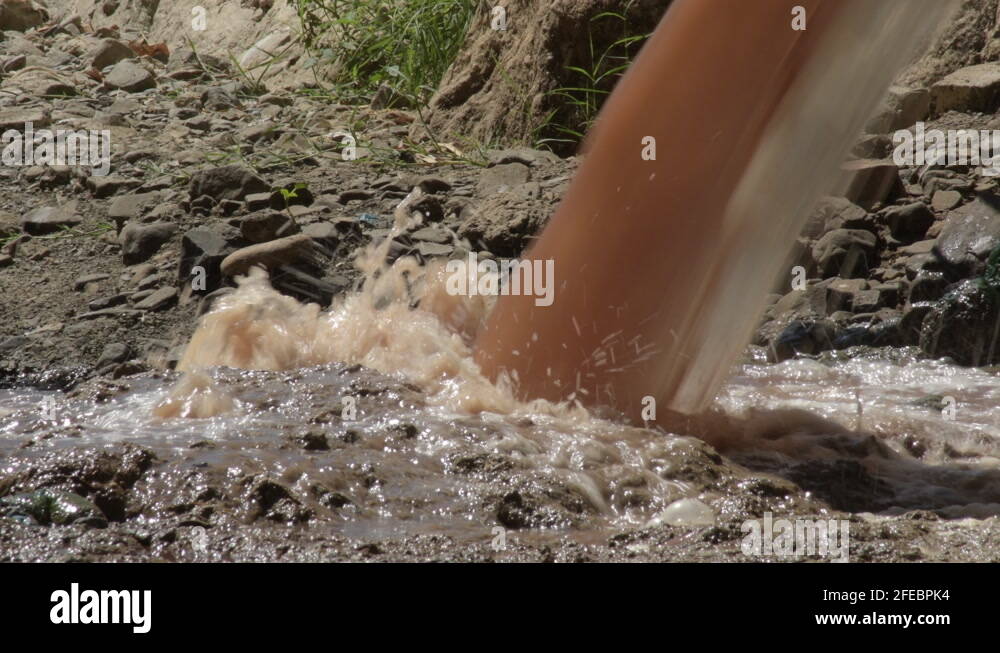 Sewage shit falling from a sewer collector into the mouth of a river ...