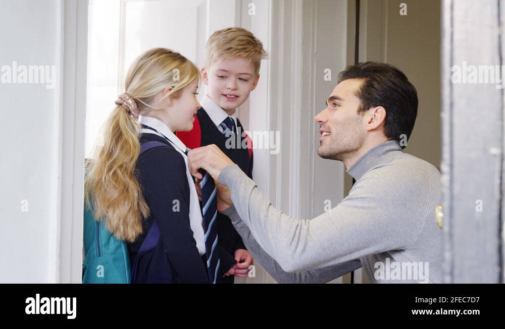 Father Saying Goodbye To Son And Daughter Wearing School Uniform As ...
