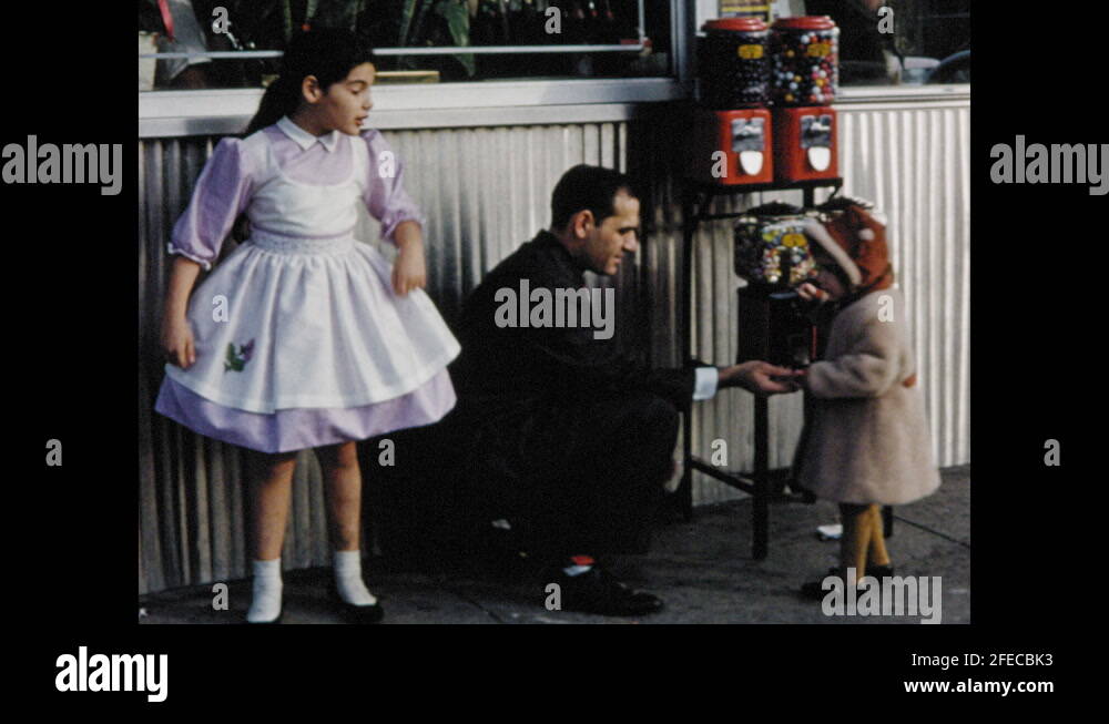 1960s: Girl gets candy from candy machine and hands to man. Girl gets ...