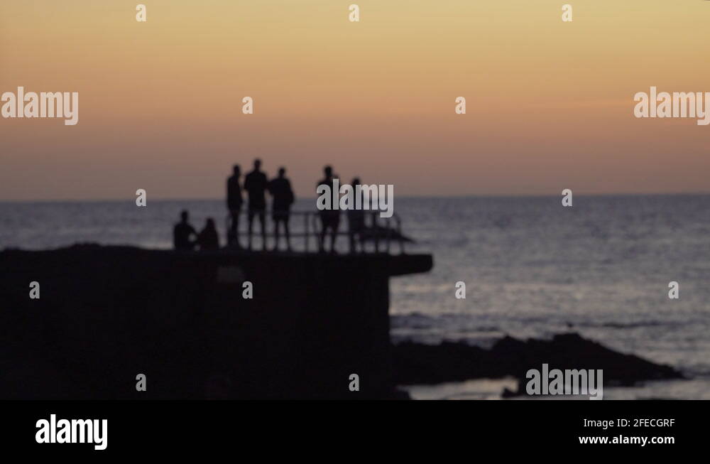 People standing and watching the sunset facing the ocean Stock Video ...