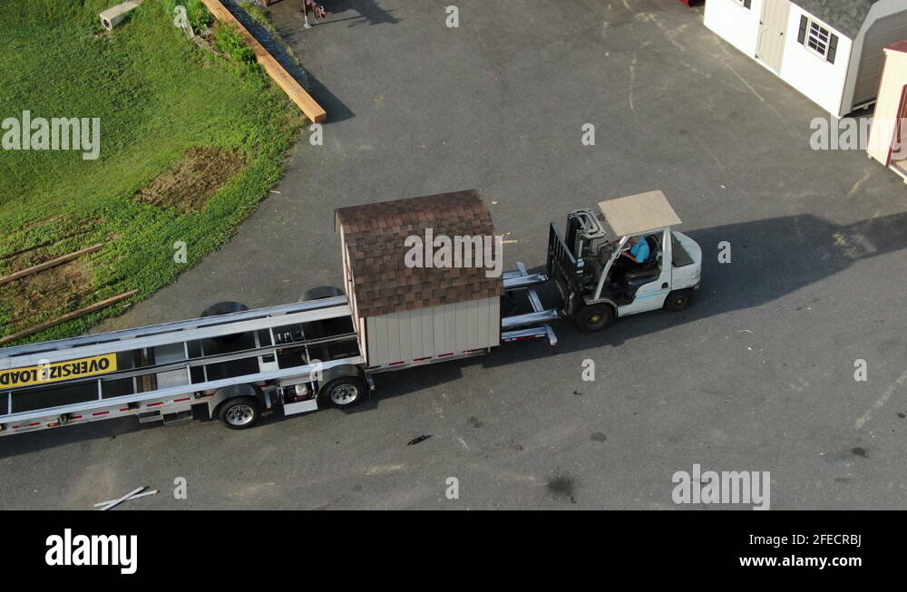 Amish man loads outdoor shed barn onto oversize load trailer, shed ...