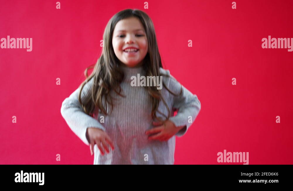 Young Girl Jumps Up Into Frame Against Red Studio Background Smiling ...