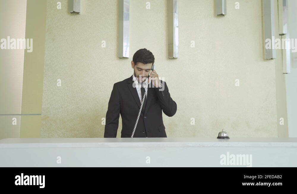 A receptionist or concierge man with uniform at front desk counter in ...