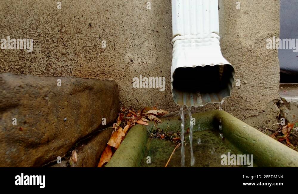 Water is seen dripping out of a rain guttering onto the ground Stock ...