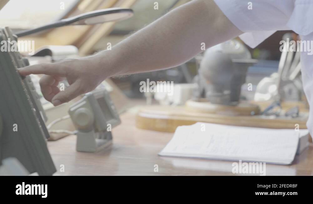 The hand of a captain is pointing at a screen which is a device used ...