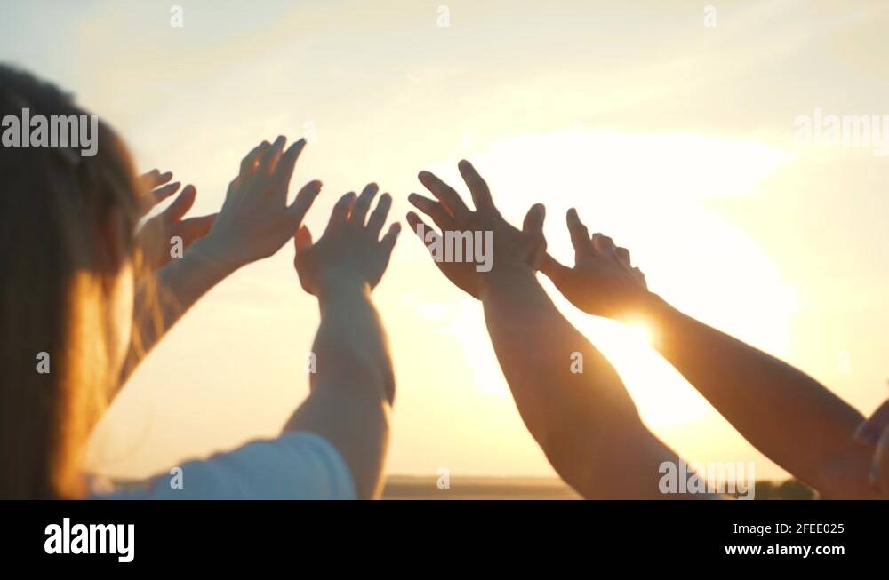 People's hands reach out to the sun and god at sunset. Happy family ...