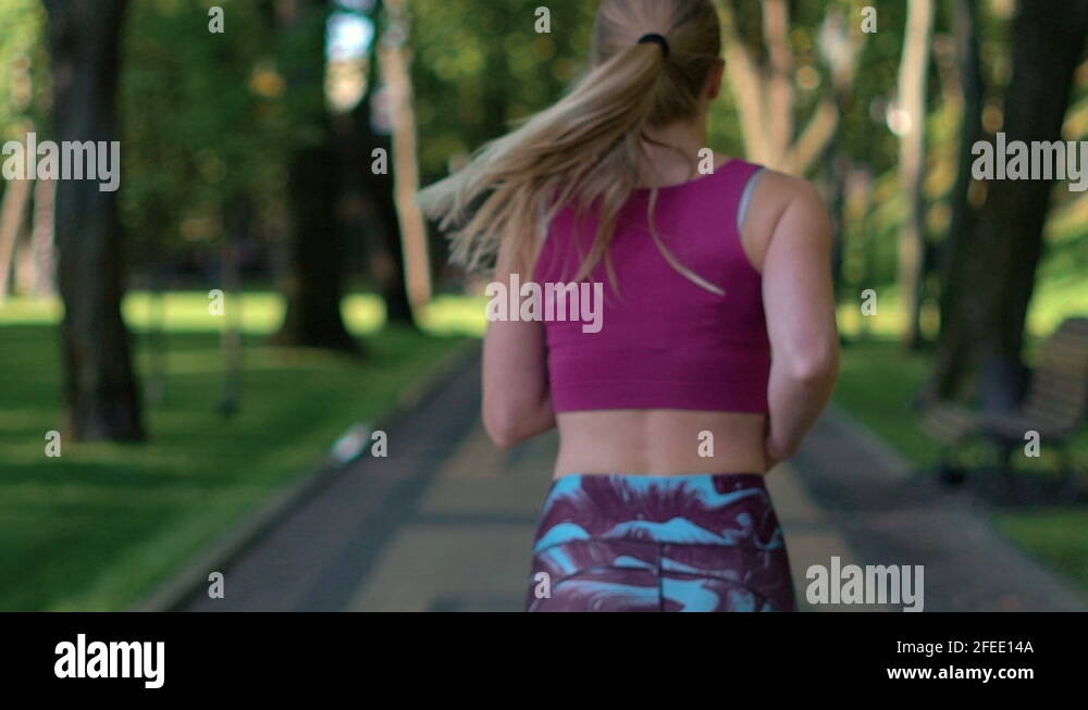 back view. muscular blonde girl runs in the park. slow motion. FullHD ...