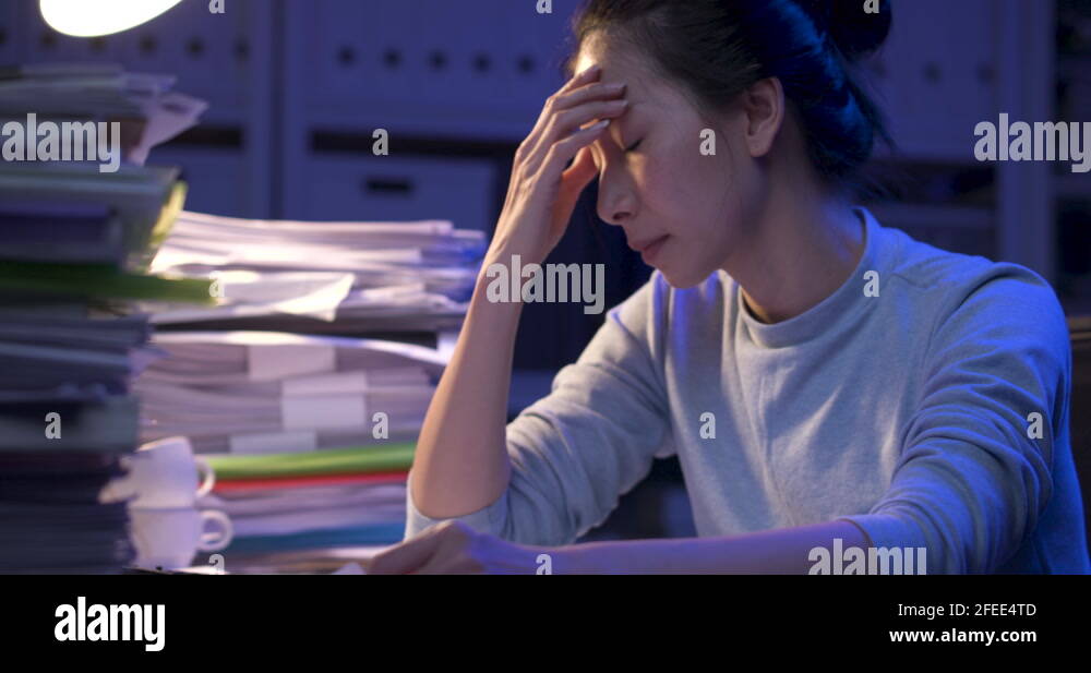 Tired asian woman lay down on desk while working hard at late night ...