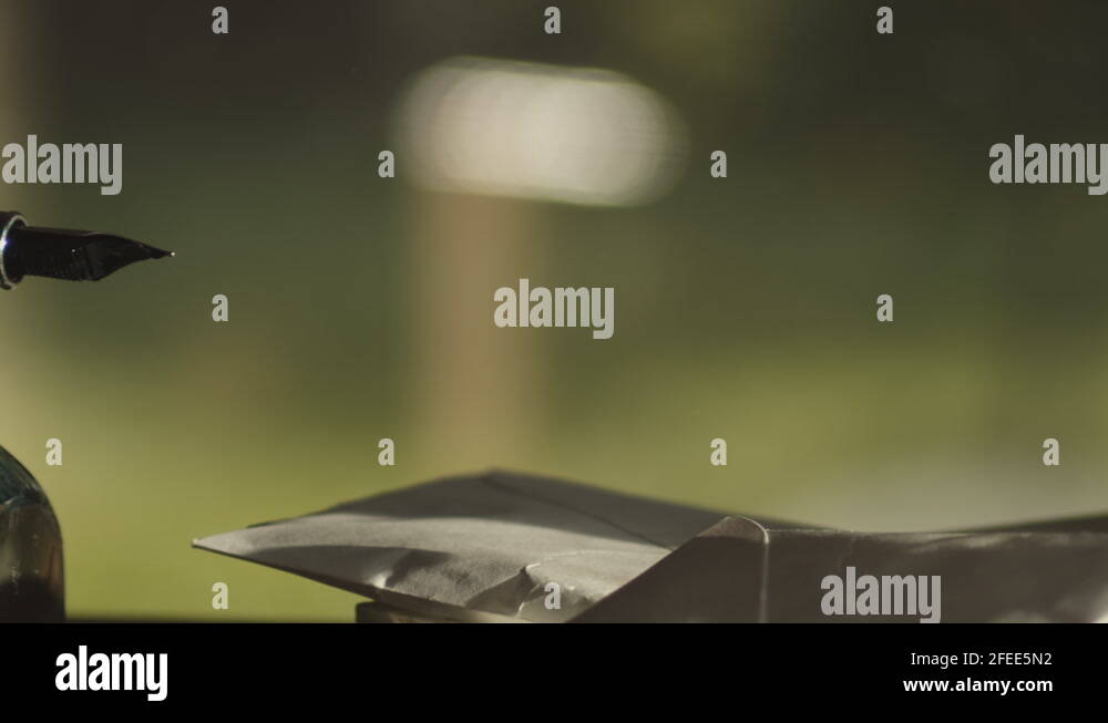 Two envelopes next to an old-fashioned fountain pen balancing on an ink ...