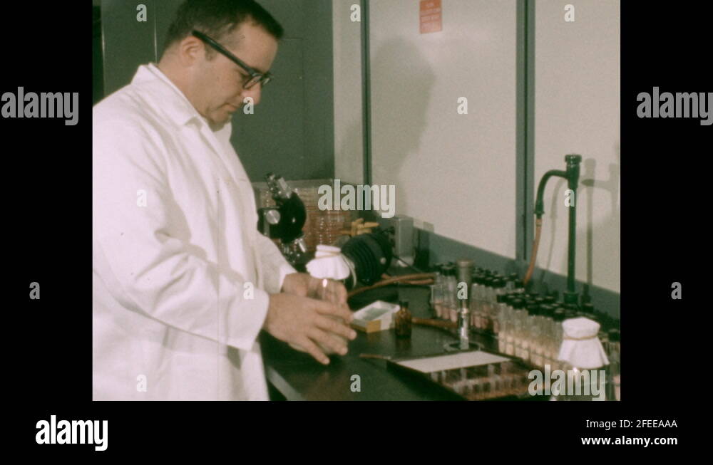 1950s: Science laboratory with microscope. Scientist in lab coat places ...