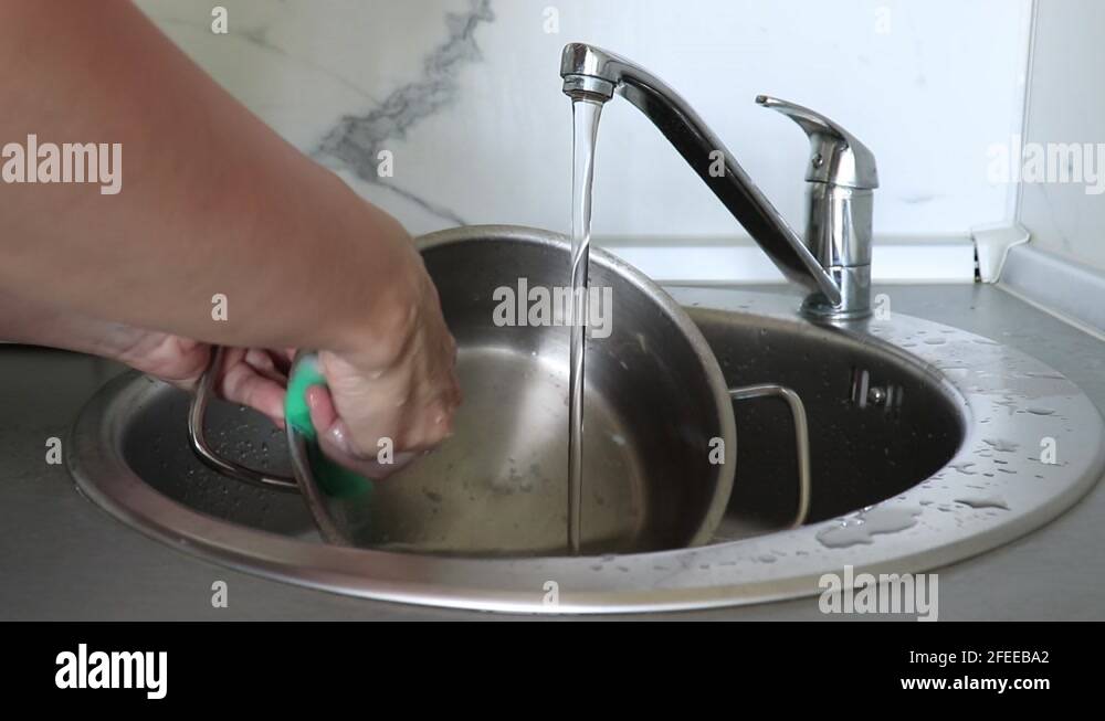 Washing pan in kitchen sink with soap and water by hands, household and ...