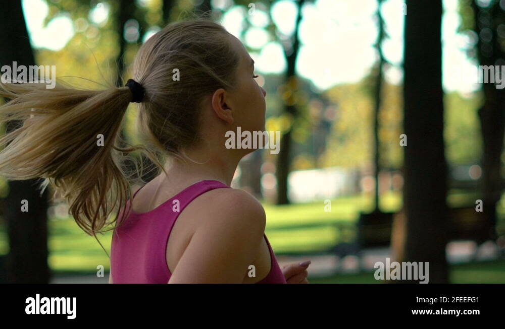 back view. muscular blonde girl runs in the park. slow motion. FullHD ...
