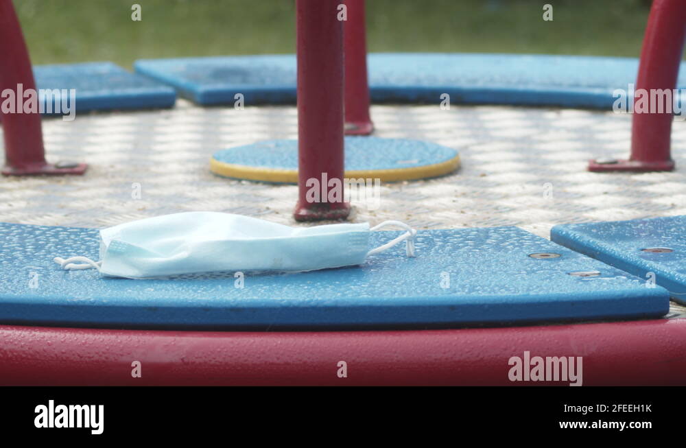 A covid-19 face mask left on a playground roundabout slowly rotating ...
