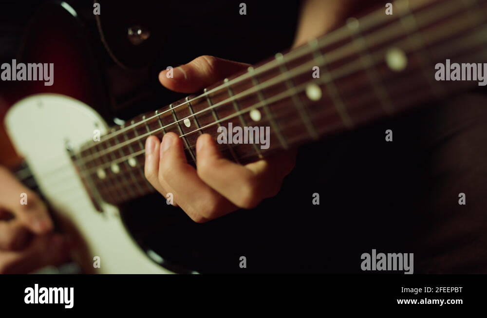Musician playing electric guitar in studio. Guitarist hand pinching ...