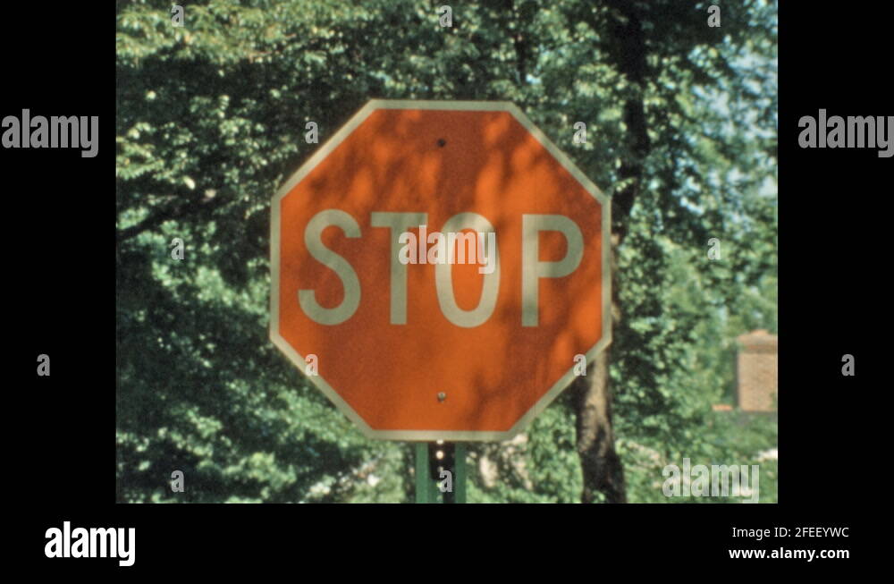 1960s: Close up of stop sign. Crossing guard in street, boy and girl ...