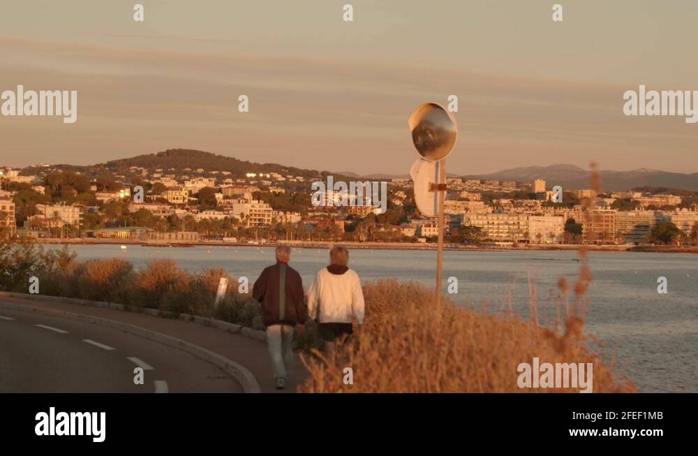 Two people having their morning walk together next to a city on the sea ...