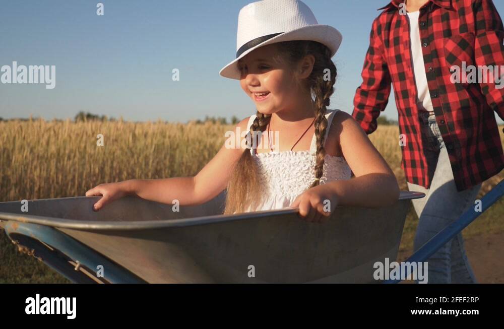 Children play with a garden cart, a baby ride on a wheelbarrow. happy ...
