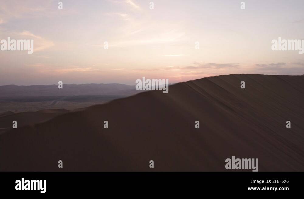 Stunning reveal shot of wide open desert passing top of dune during ...
