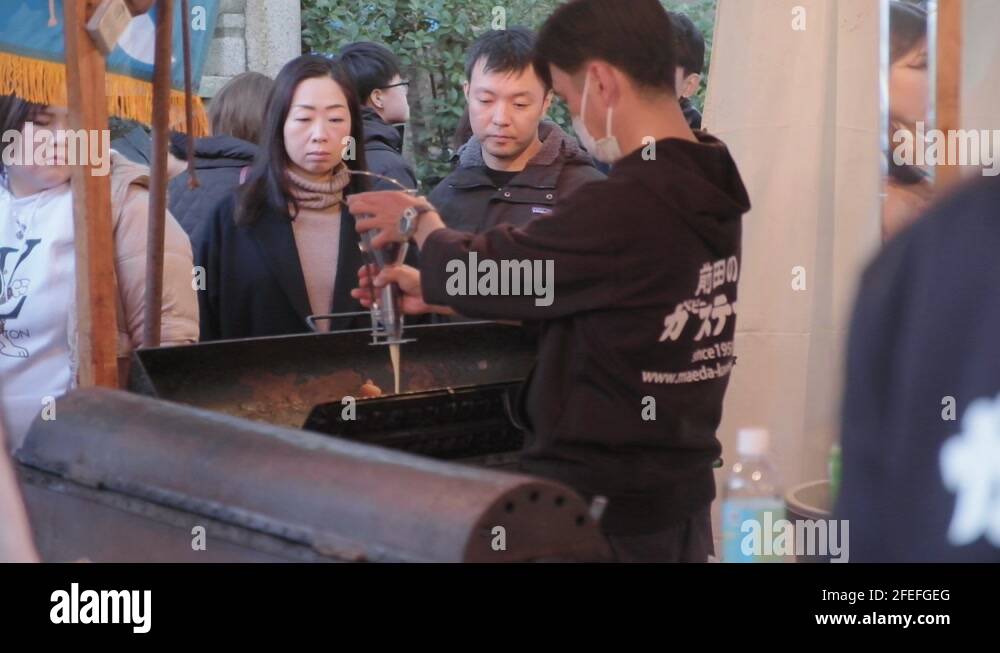 Back view of chef pouring batter into mold at food stand to make egg ...