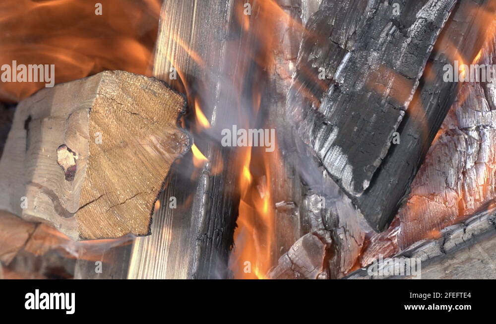 Wooden logs burn in bonfire, enveloped in red flame. Vertical format ...
