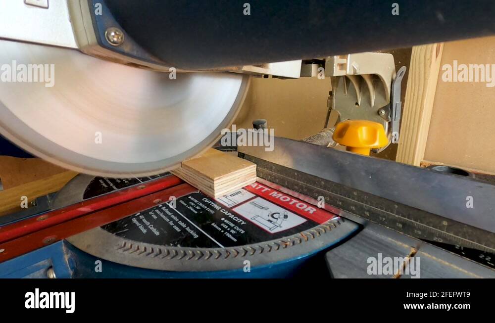 Woodworking workshop crosscut saw cutting a piece of wooden plank close ...