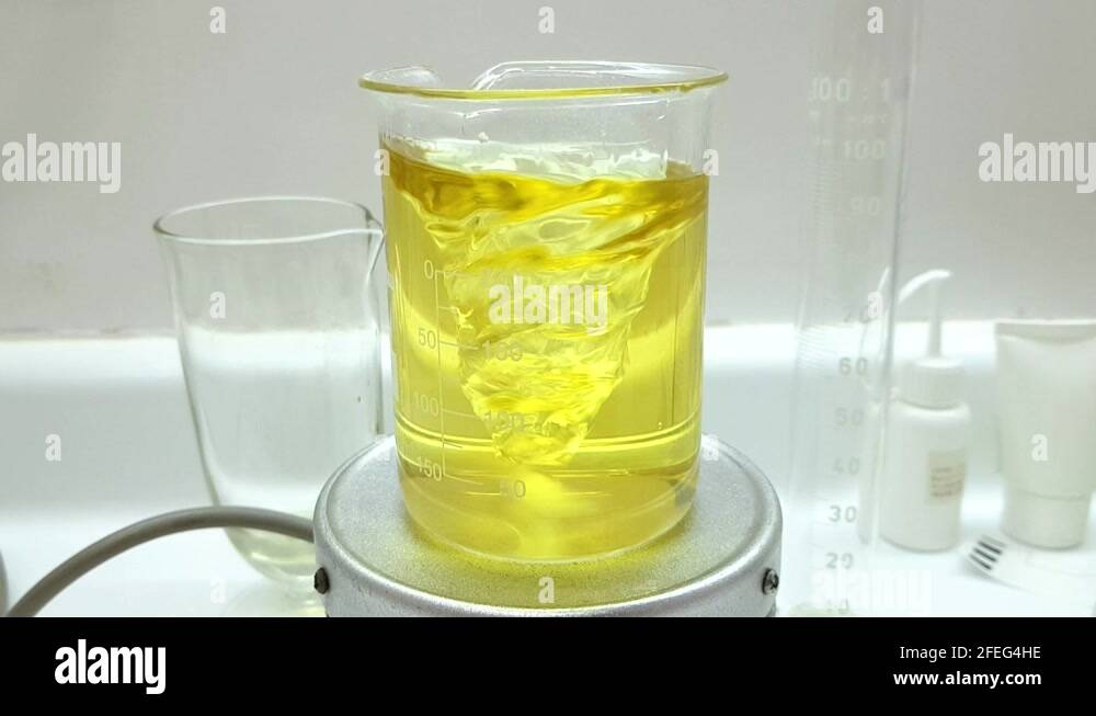 yellow chemical solution spinning in beaker on magnetic stirrer, close ...